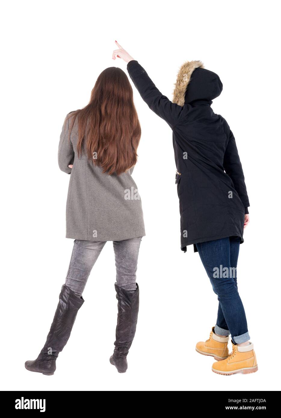 Back view of two pointing young girl in winter jacket. Rear view people ...