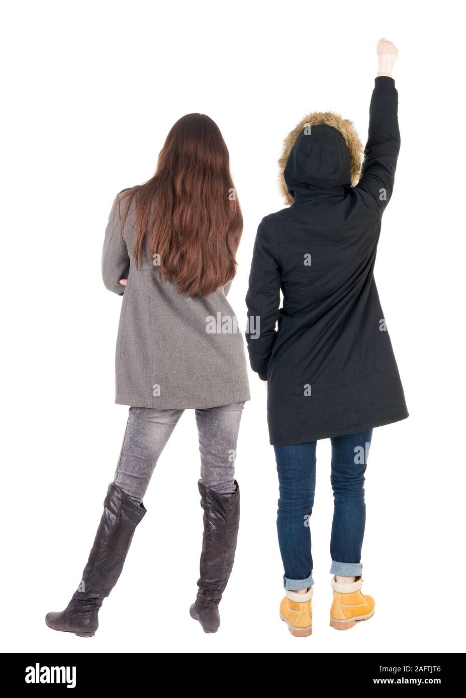 Back view of two pointing young girl in winter jacket. Rear view people ...