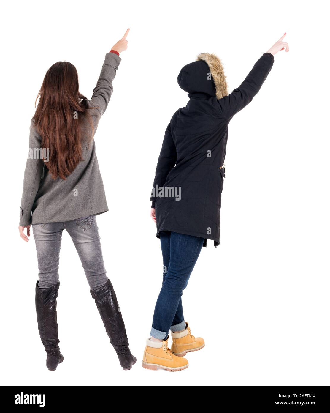 Back view of two pointing young girl in winter jacket. Rear view people ...
