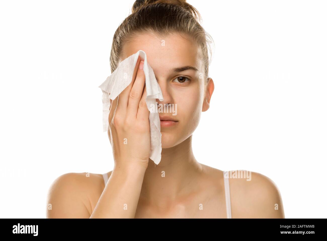 Young woman cleaning her face with wet wipe on white background Stock ...