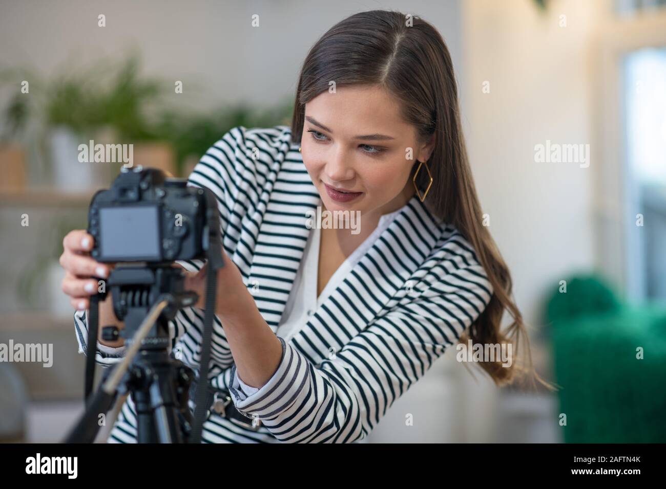 Beautiful young woman setting up the camera Stock Photo - Alamy