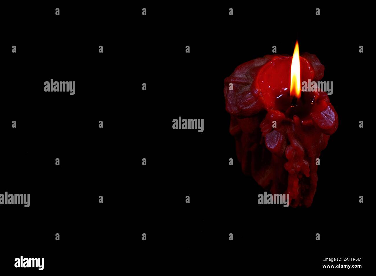 Single red burning candle on black. Copy space. Candle has been burning ...