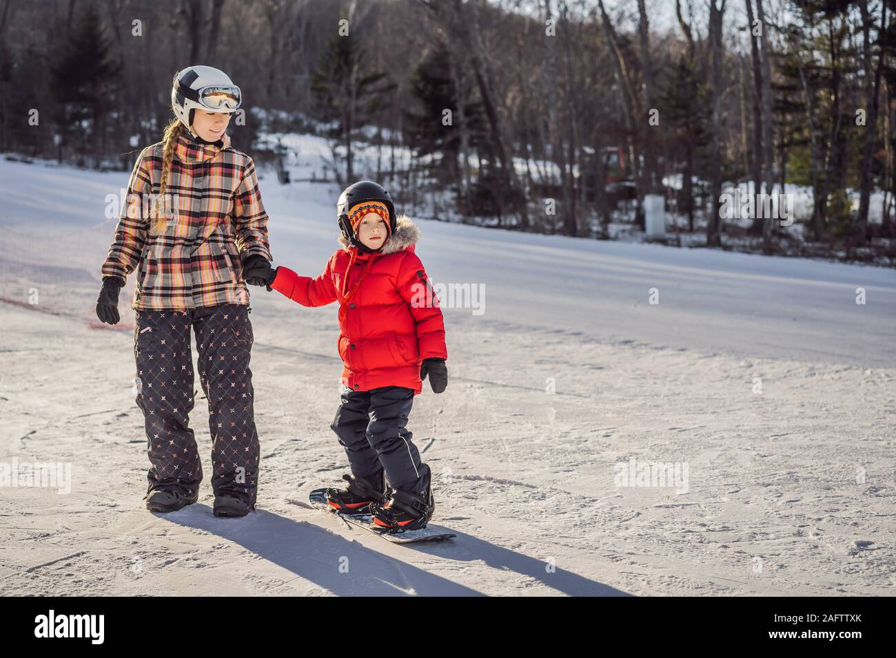 Mother teaches son snowboarding. Activities for children in winter ...