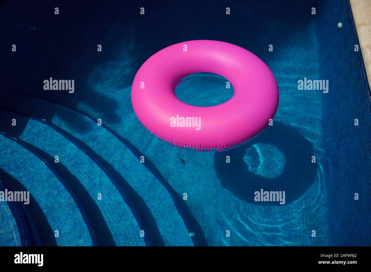 Bright pink inflatable ring in sunny blue swimming pool Stock Photo - Alamy