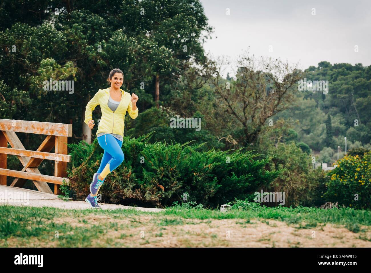 Portrait fit female personal trainer running in park Stock Photo - Alamy