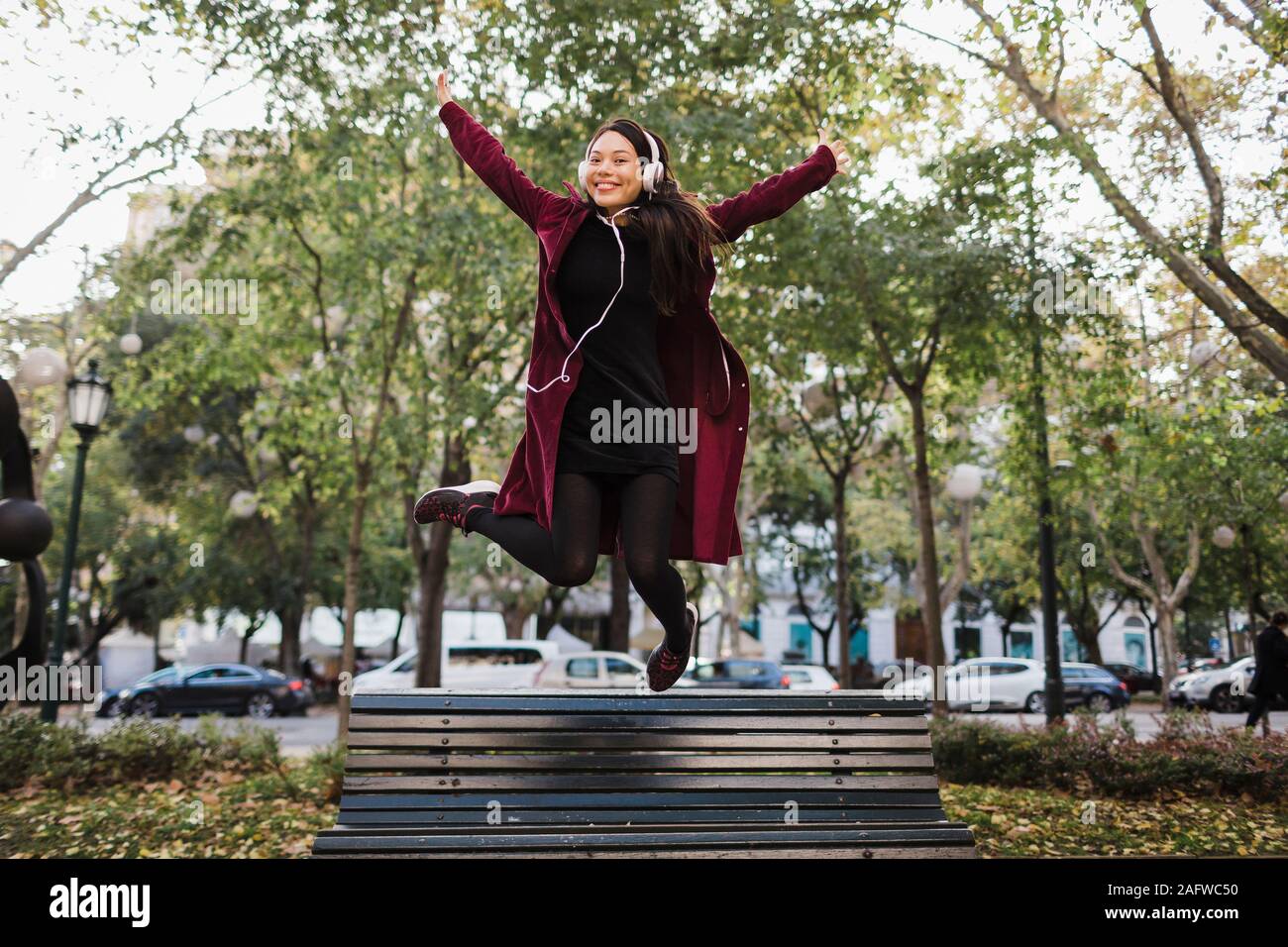 Portrait playful exuberant woman jumping off urban city bench Stock ...