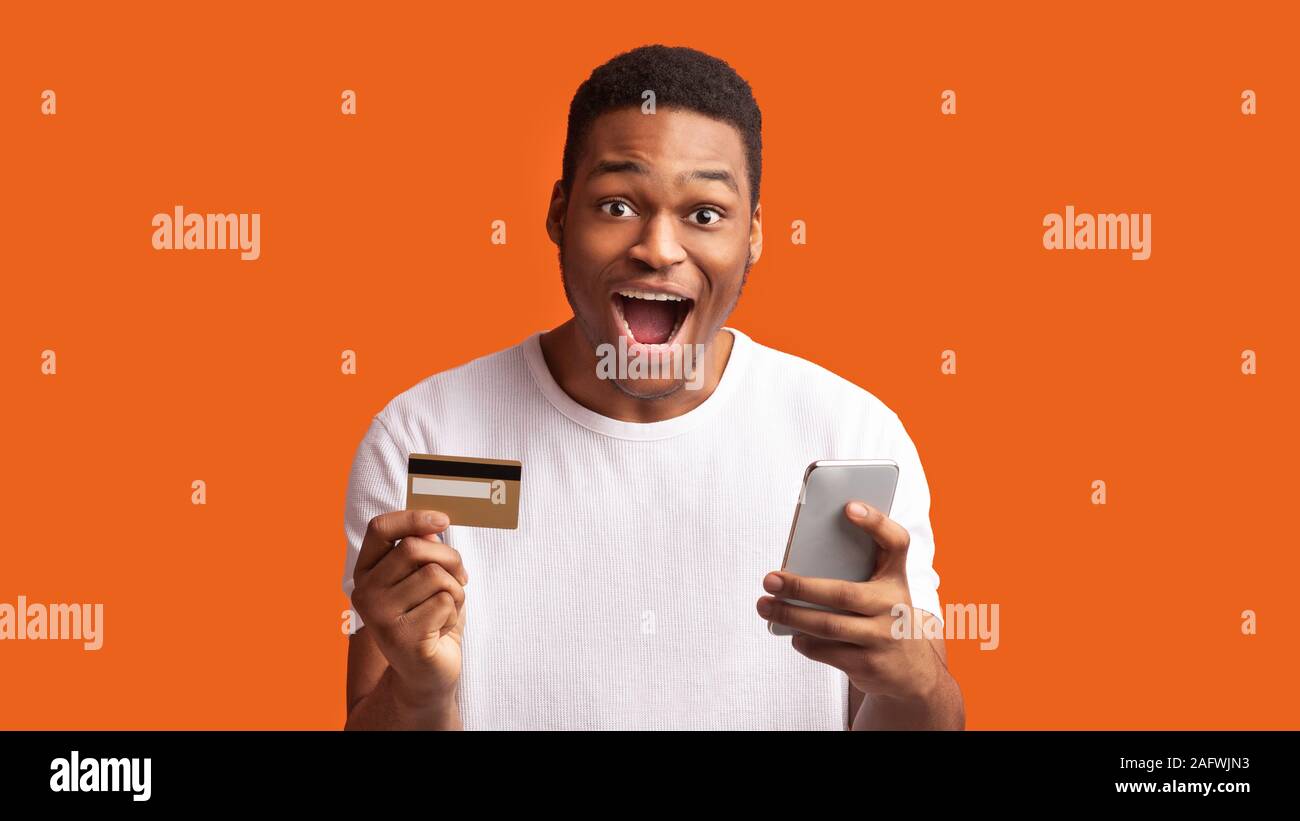 Black man holding credit card and cellphone at studio Stock Photo - Alamy