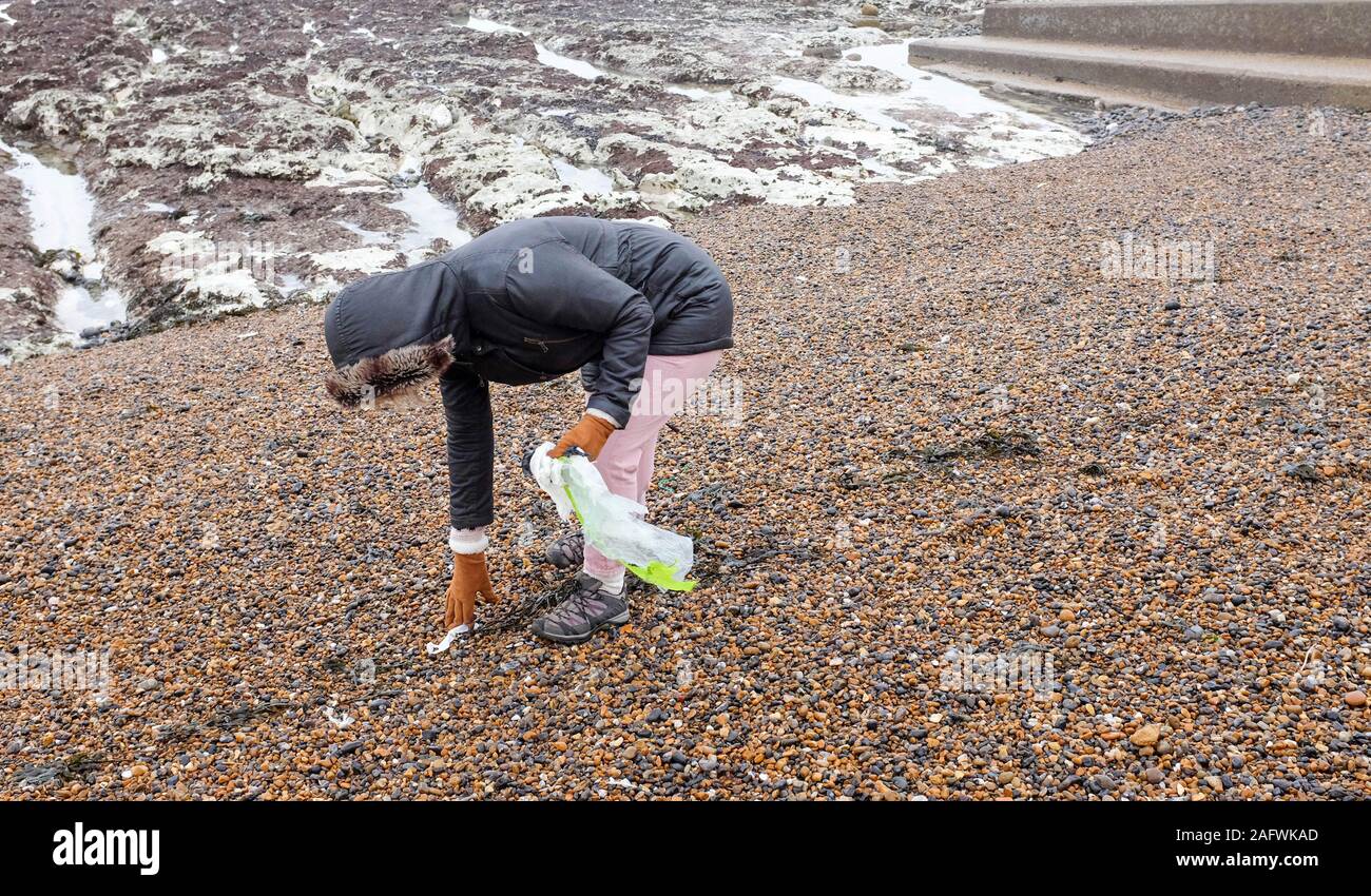 Woman collecting rubbish plastic trash waste bags etc from a beach near ...