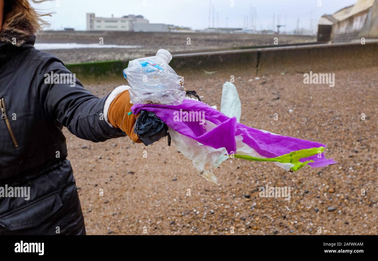 Woman collecting rubbish plastic trash waste bags etc from a beach near ...