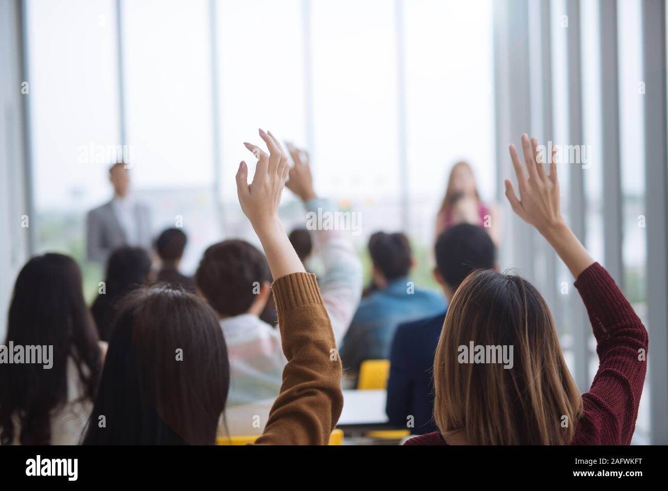 Raised up hands and arms of large group in seminar class room to agree ...