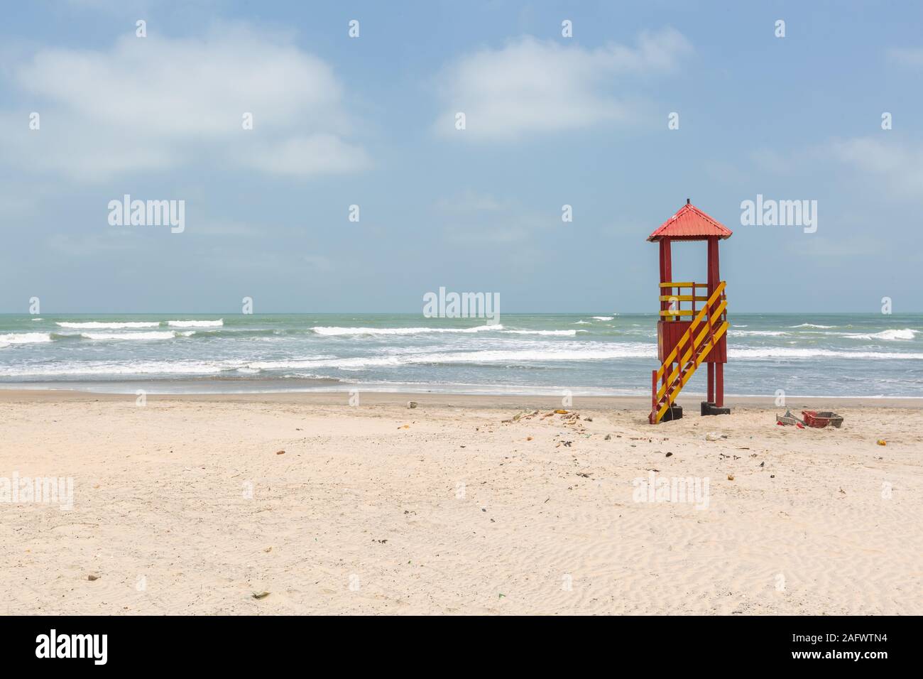 Red watchtower with a yellow ladder at the beach with the sea in the ...
