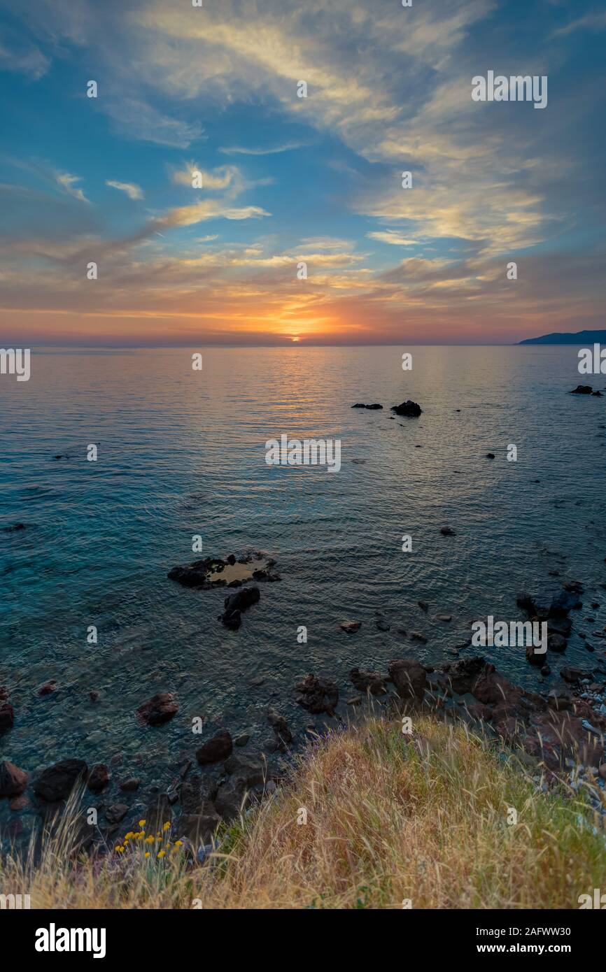 Vertical shot of the sunset over the beautiful calm ocean captured in ...