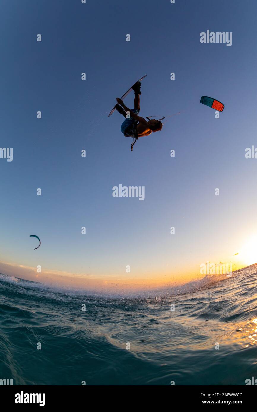 Vertical shot of a person surfing and flying a parachute at the same ...