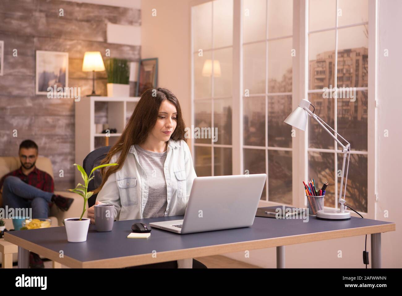 Caucasian female entrepreneur holding a cup of coffee while working on ...