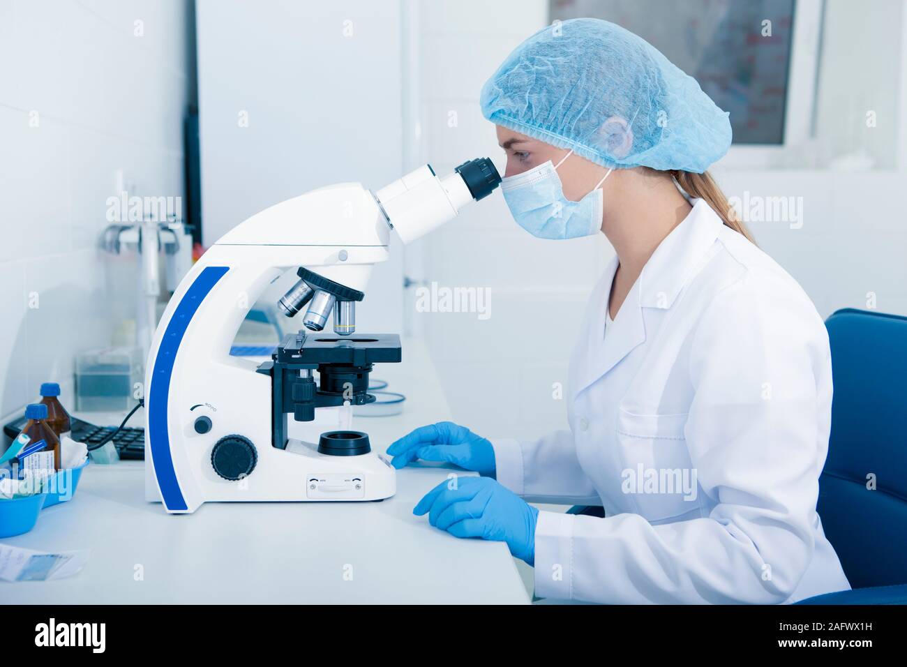 Young female Medical worker looking in microscope Stock Photo - Alamy