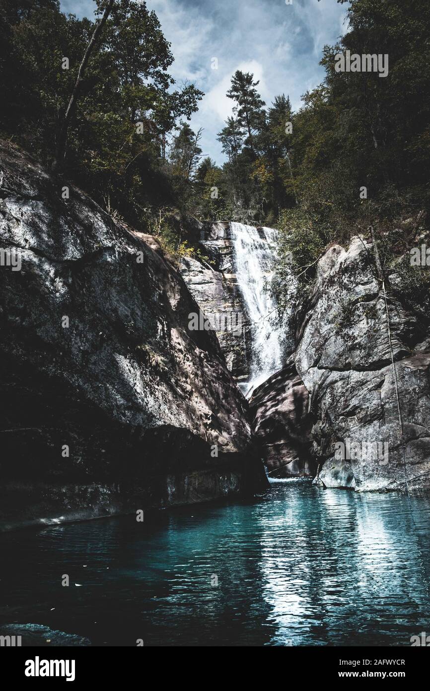 Vertical shot of a waterfall flowing from the middle of a rocky scenery ...