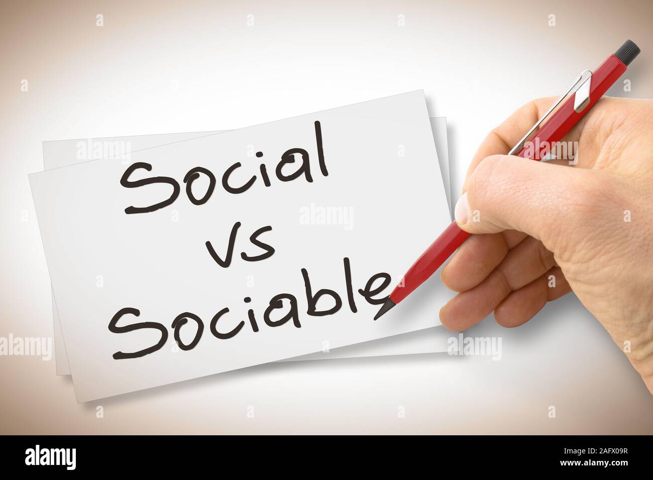 Hand writing Social Vs Sociable with a pencil on a blank sheet ...