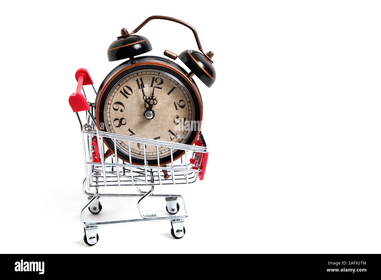Retro alarm clock in shopping cart on white background Stock Photo - Alamy