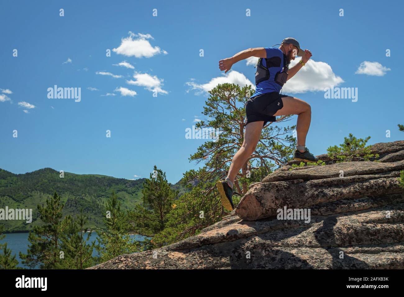 Runner Climbing a Rock. The athlete runs on the rocks in the mountains ...