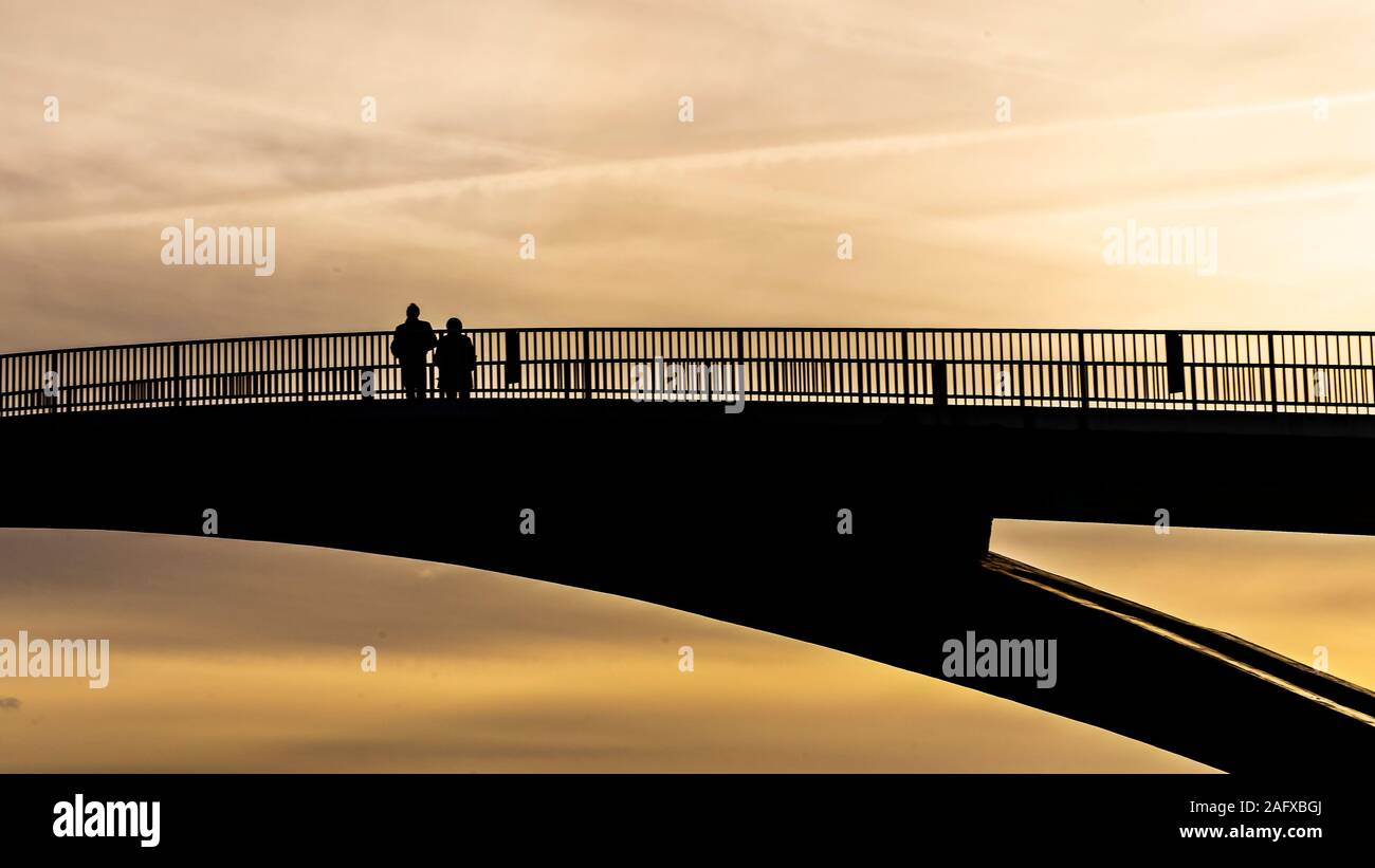 Two people looking from the bridge in to the distance, backlight shot ...