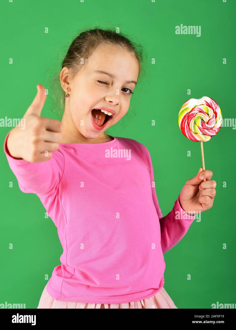 Lady holds round shaped lollipop. Child with cheerful face poses with ...