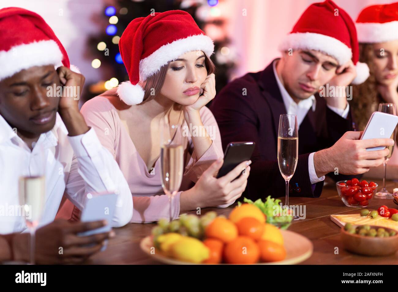Bored Friends Using Mobile Phones During Christmas Party Sitting Indoor ...