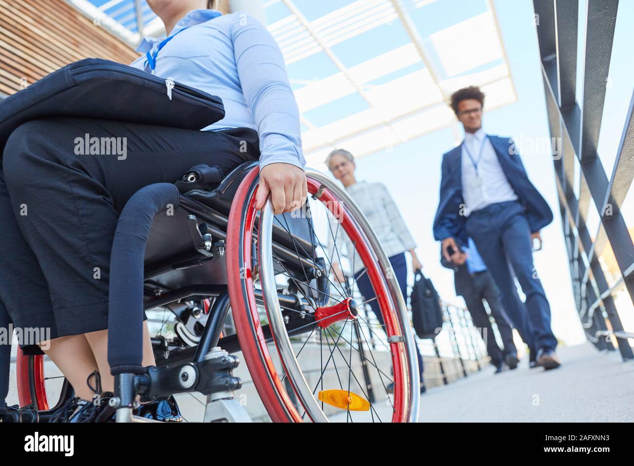 Workers and disabled woman in a wheelchair on a ramp in front of the ...
