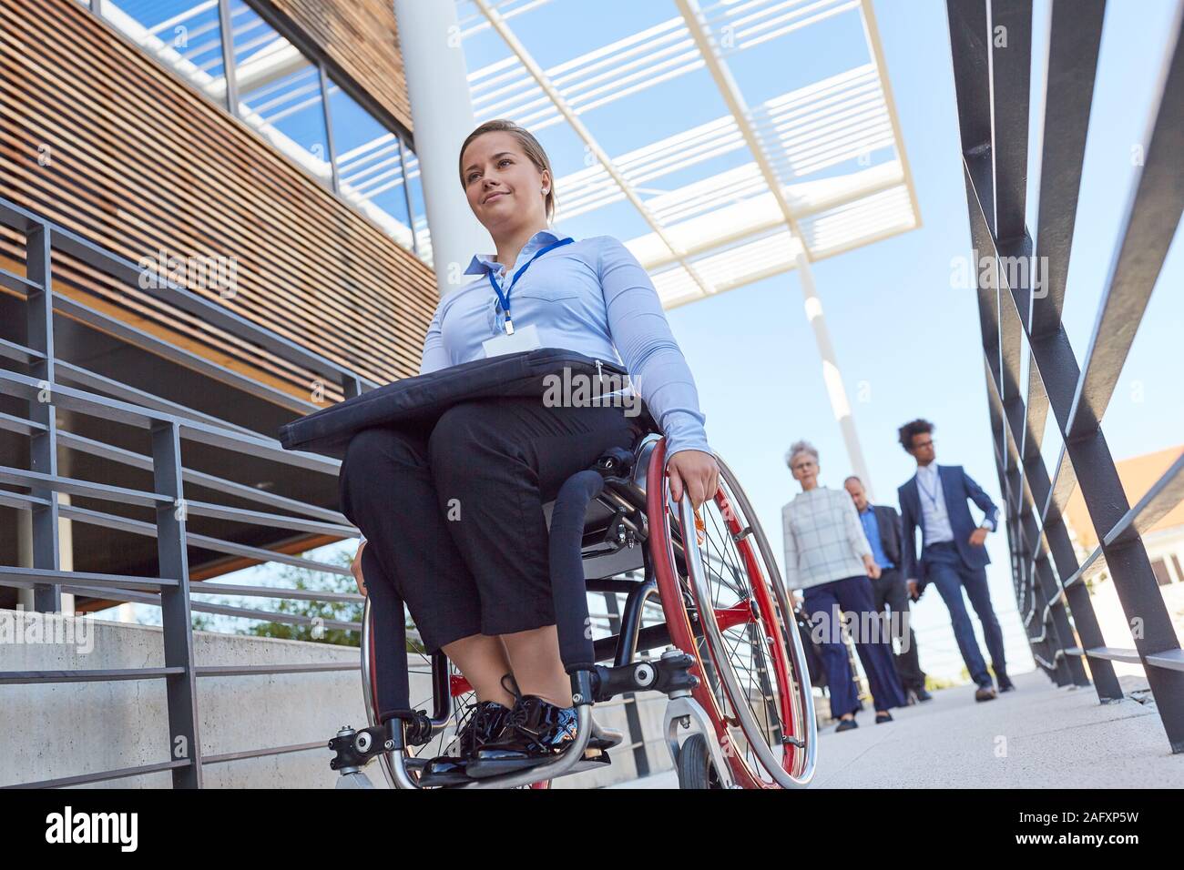 Disabled businesswoman in a wheelchair on a ramp to the office for ...