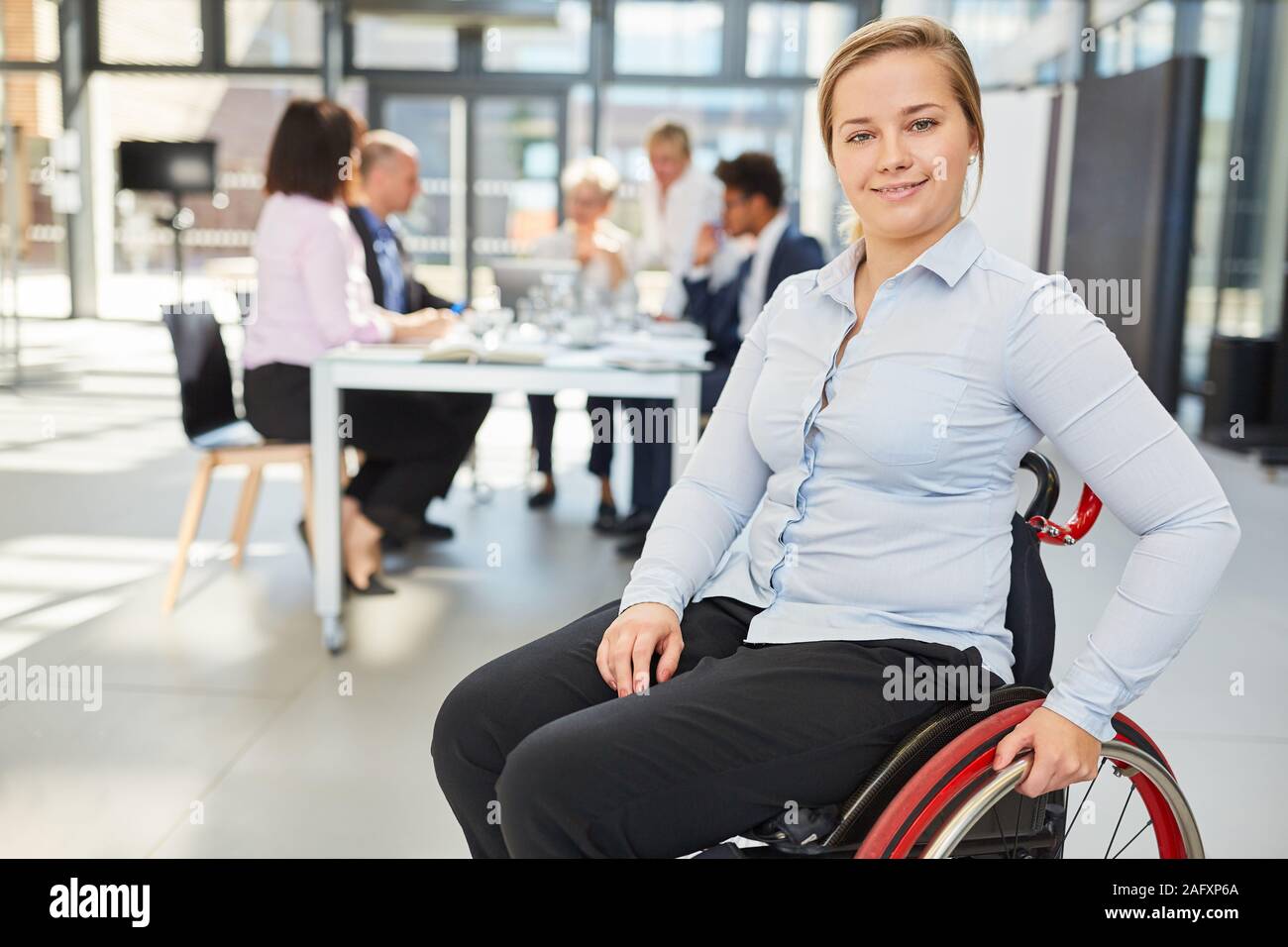 Woman sitting in a wheelchair in the office as a business inclusion ...