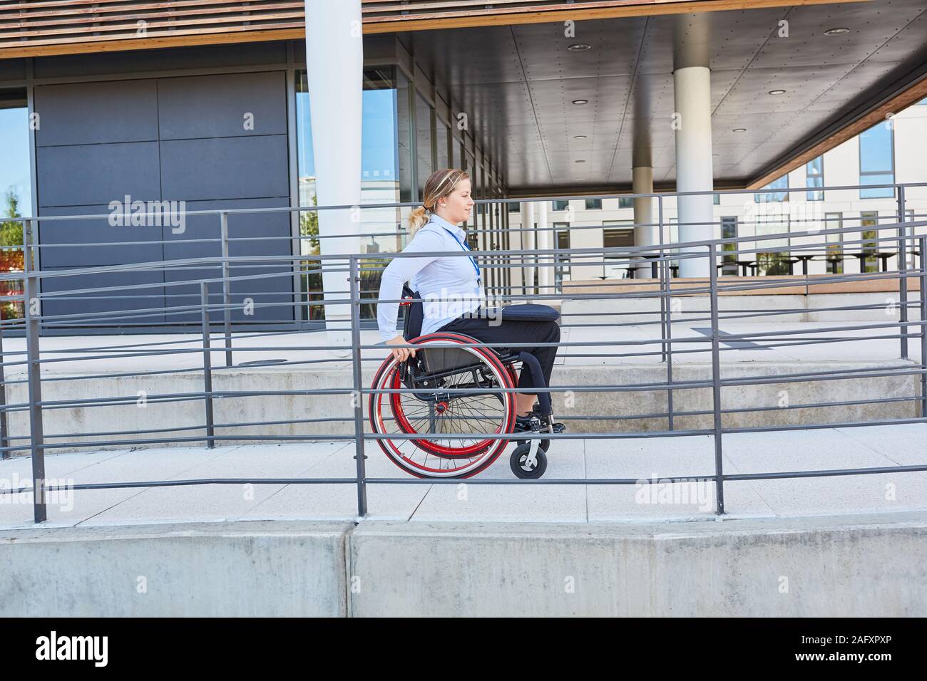 Disabled woman in a wheelchair traveling on a ramp to the business ...