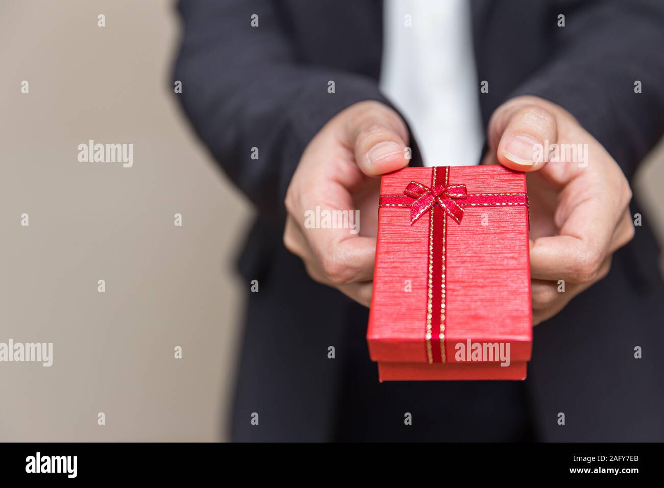 Hand giving present gift box reward in business office with space for ...