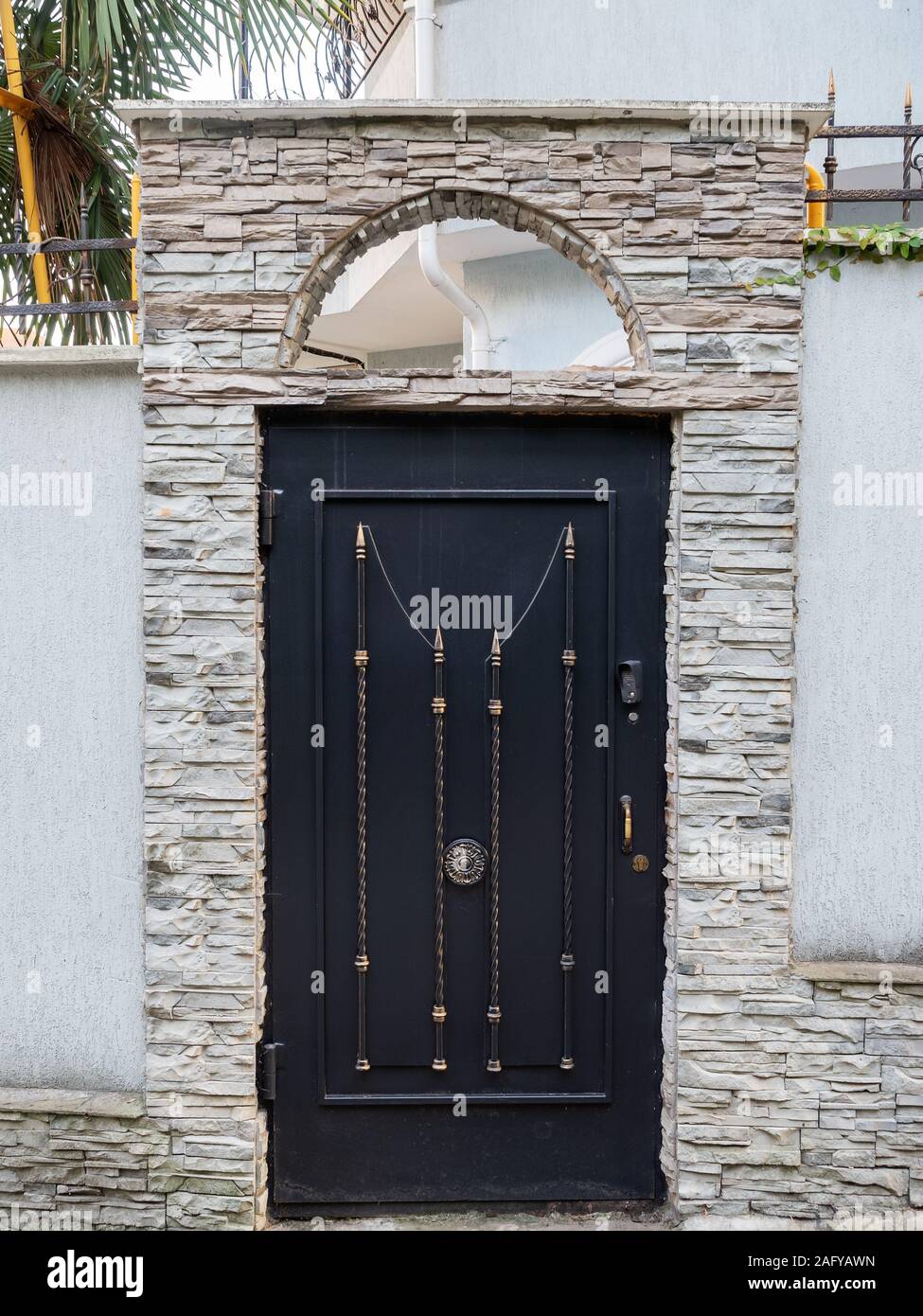Beautiful black gate with forging elements in arched stone opening ...