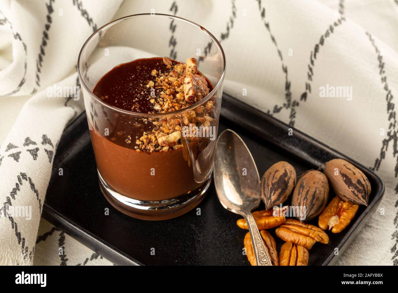 Chocolate mousse in a glass on black rectangular plate with a spoon and ...