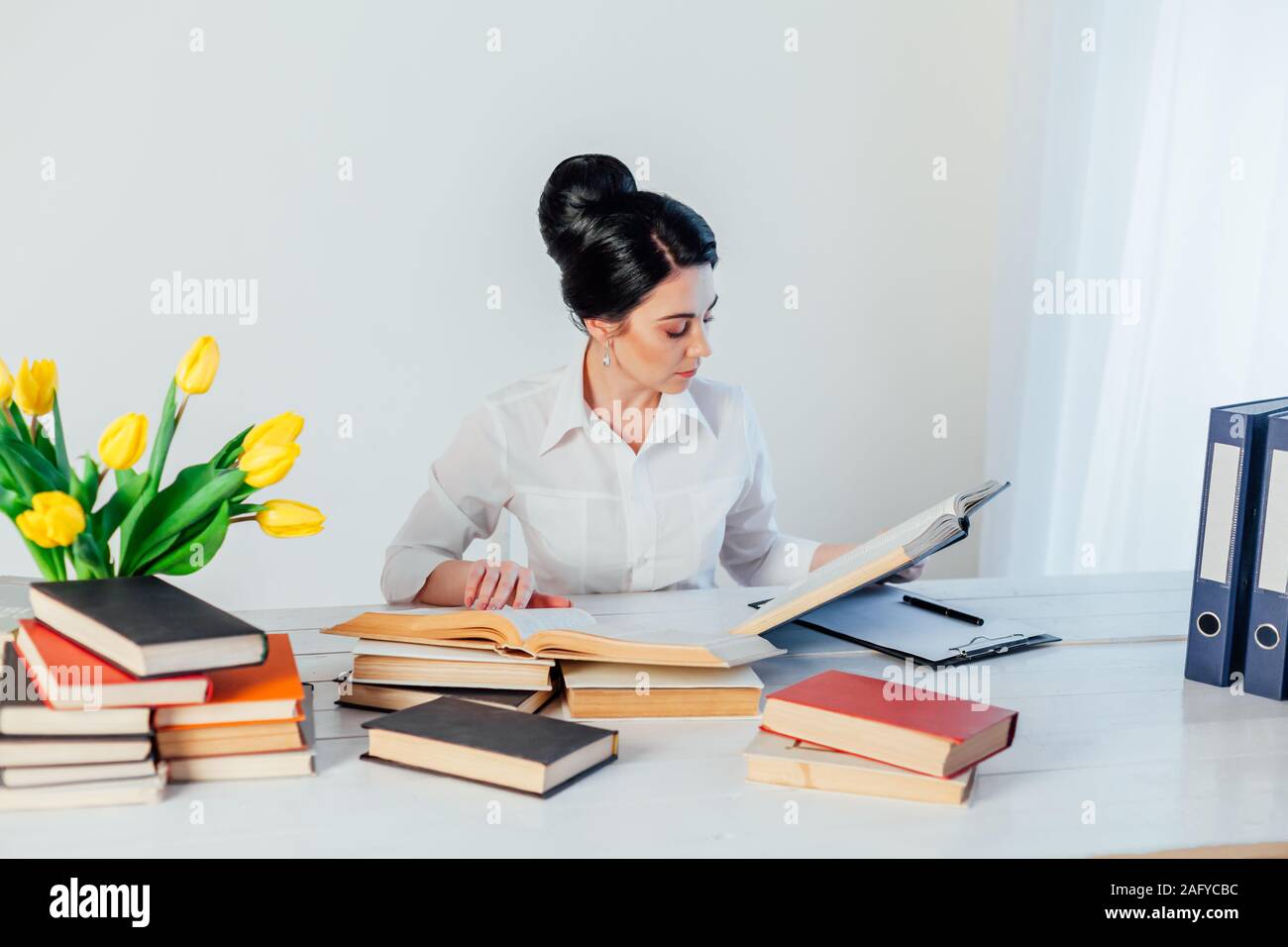 women in a business suit behind a table with books Stock Photo - Alamy