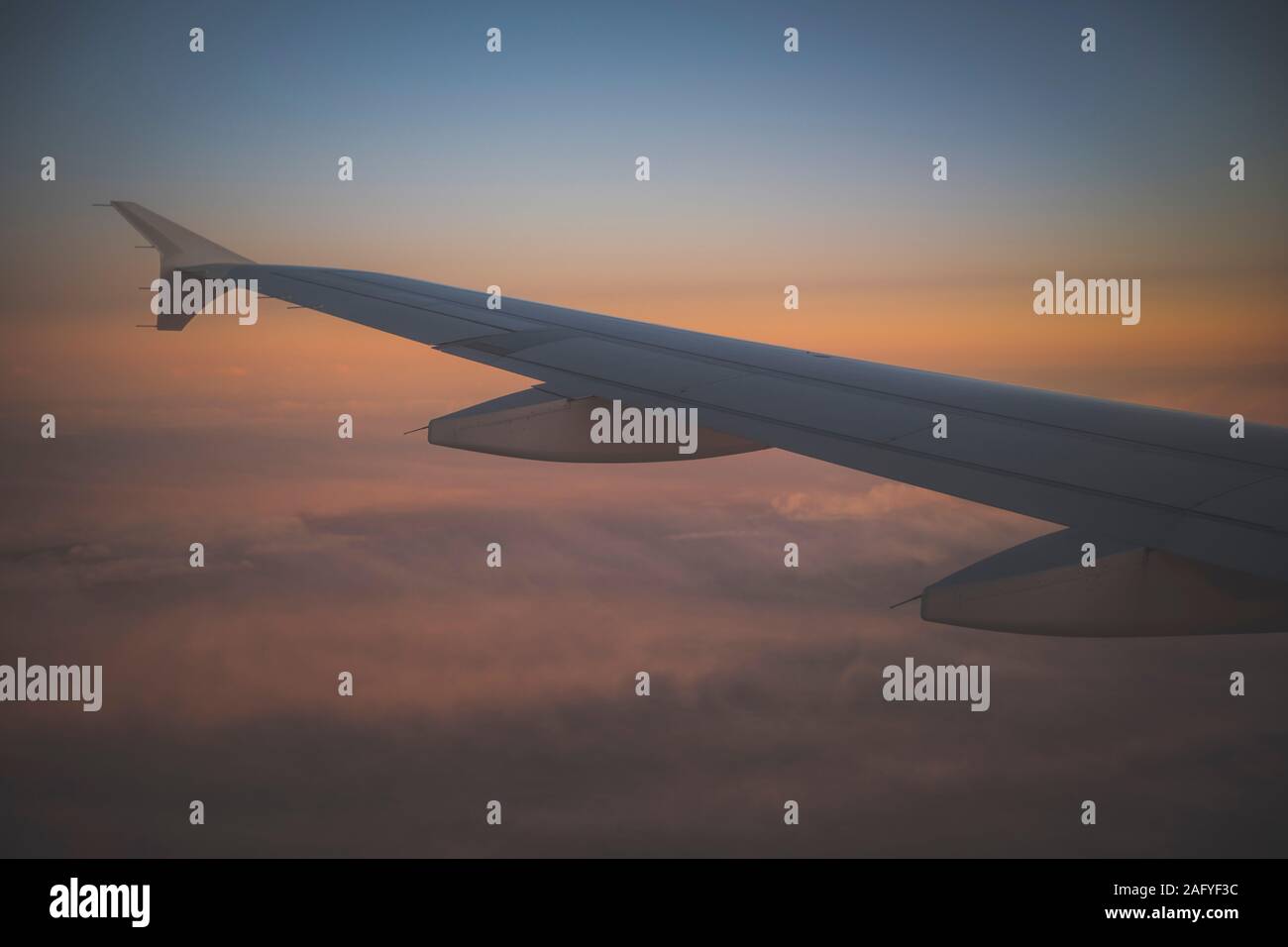 The wing of an airplane in an orange sunset sky Stock Photo - Alamy