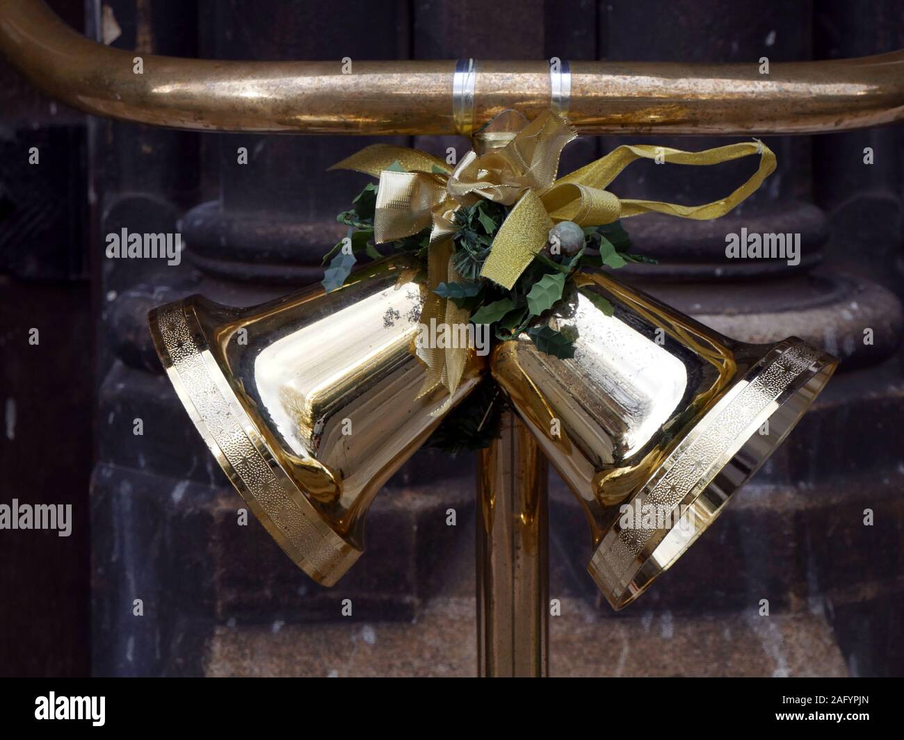 Two Christmas bells tied to a metal post Stock Photo - Alamy
