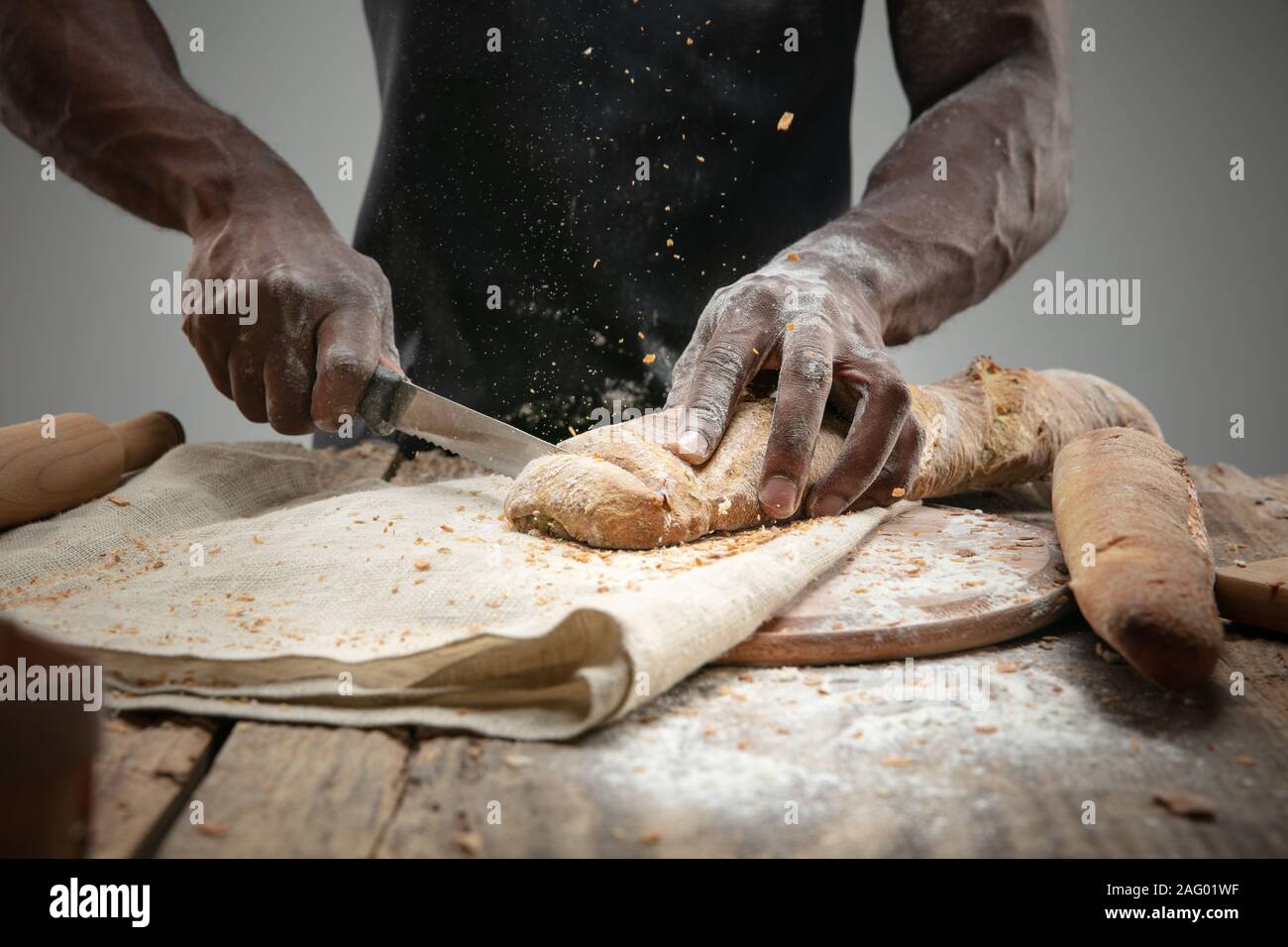 Close up of african-american man slices fresh cereal, white bread, bran ...