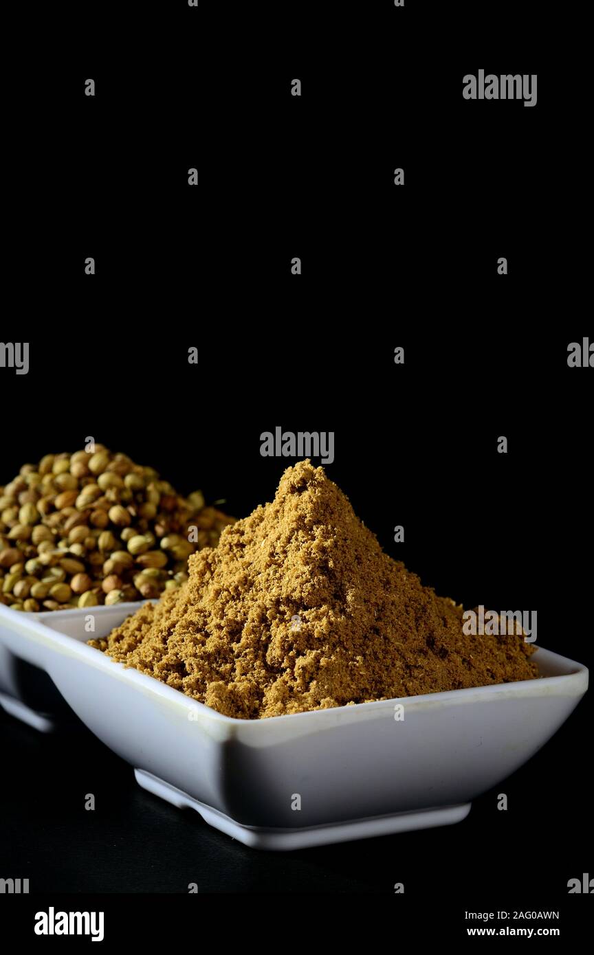 Coriander seeds and Coriander Powder in white plate on black background ...