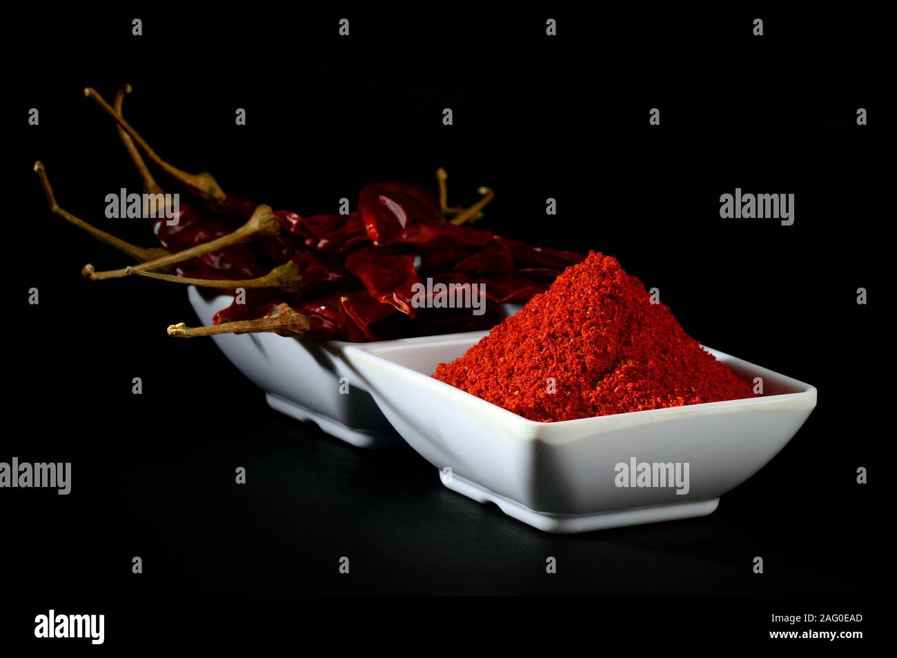chilly powder with red chilly in white plate, dried chillies on black ...