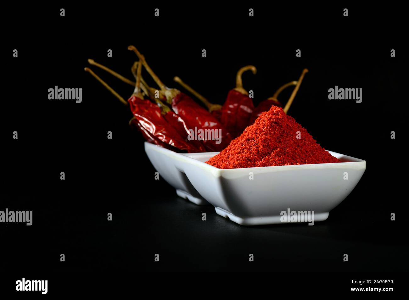 chilly powder with red chilly in white plate, dried chillies on black ...