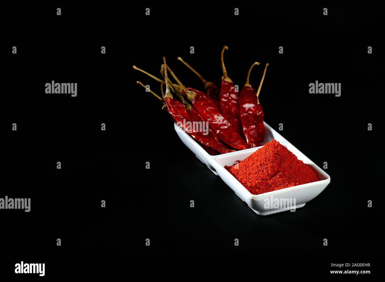 chilly powder with red chilly in white plate, dried chillies on black ...