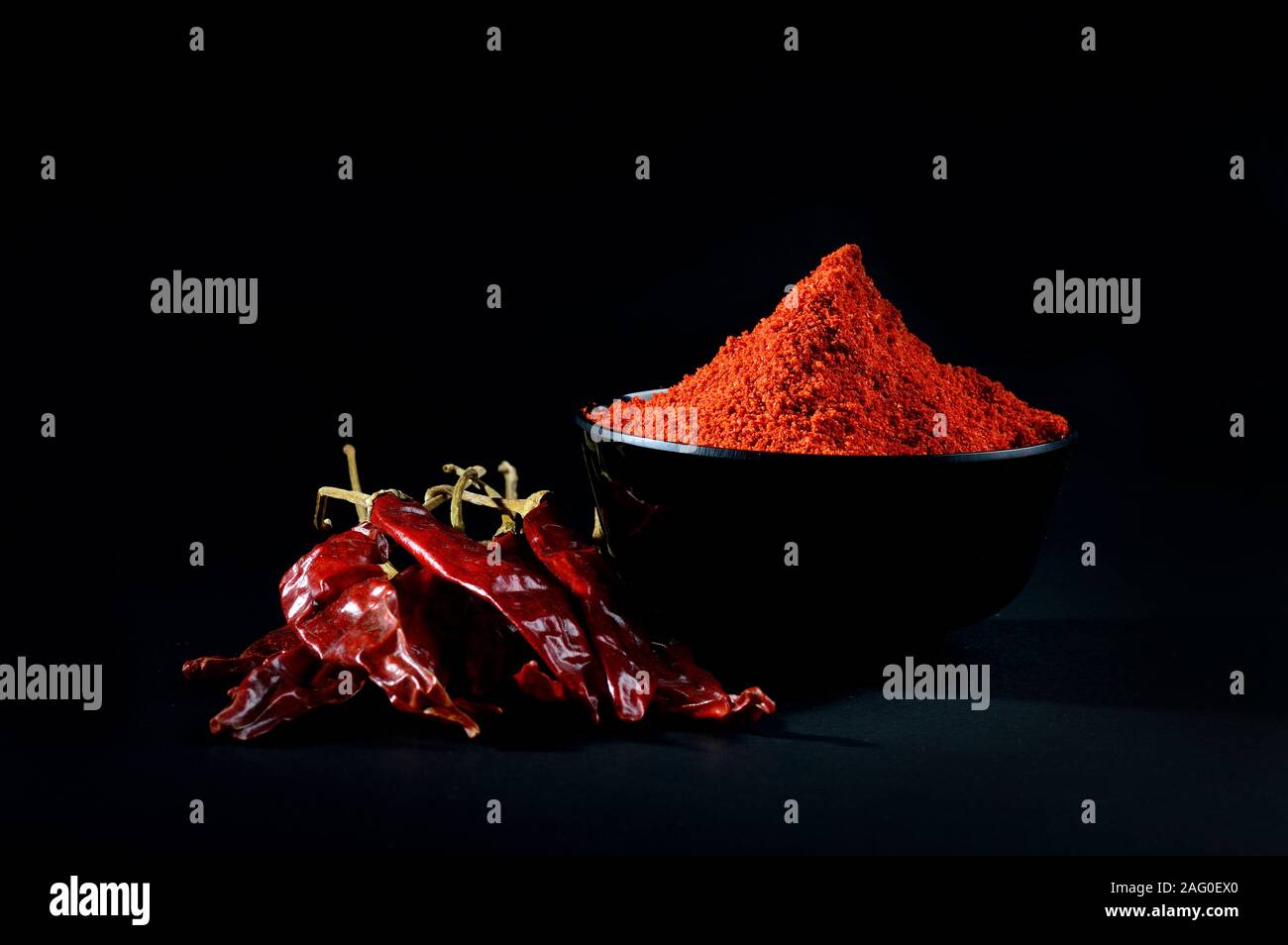 chilly powder in black bowl with red chilly, dried chillies on black ...