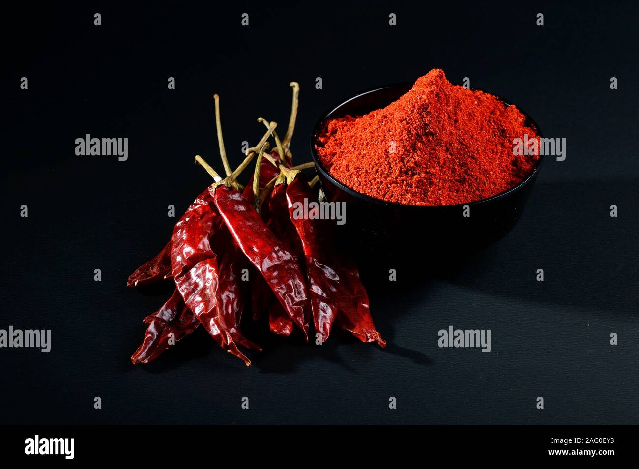 chilly powder in black bowl with red chilly, dried chillies on black ...