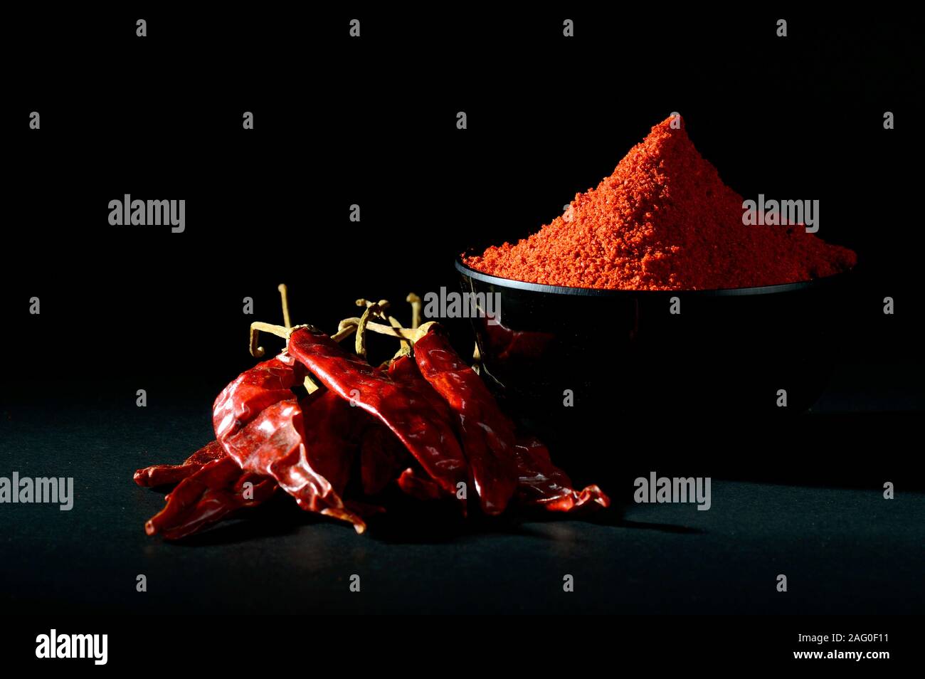 chilly powder in black bowl with red chilly, dried chillies on black ...