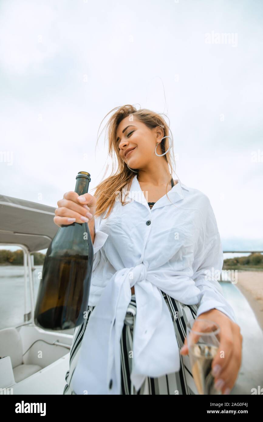 A luxurious rich woman funs yacht and holding bottle champagne Stock ...
