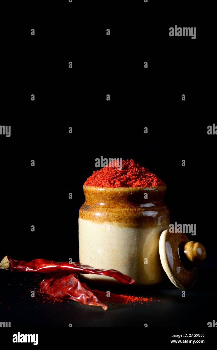 Red Chili Pepper powder in clay pot with Red Chili Peppers on black ...