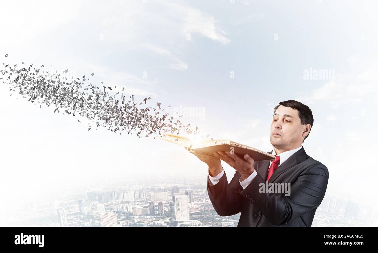 Serious businessman with open book looking up Stock Photo - Alamy