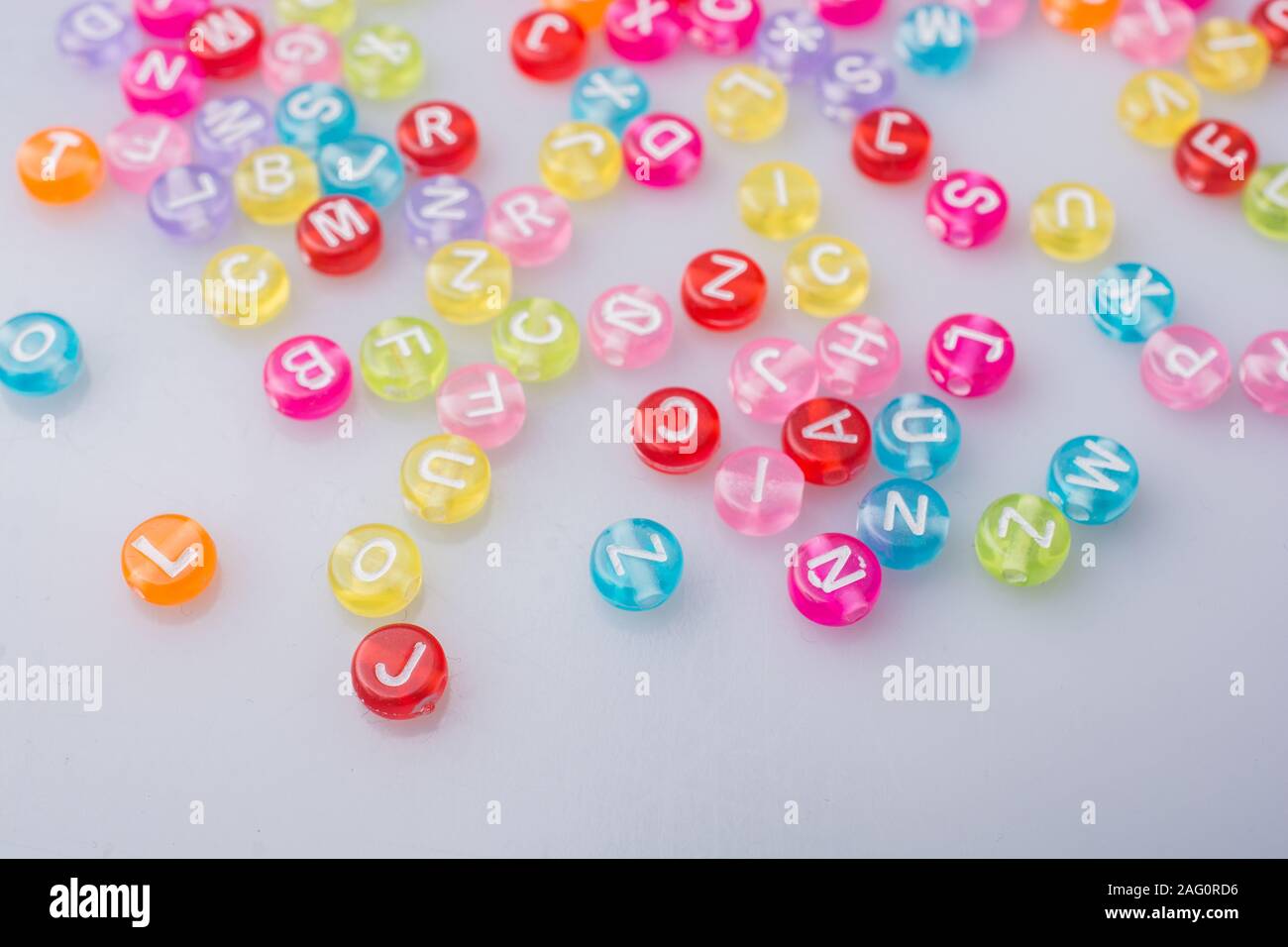 Multi color alphabet letter beads scattered randomly Stock Photo - Alamy