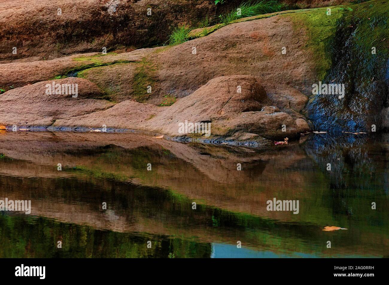 Stone rock bank reflects in a still pone Stock Photo - Alamy