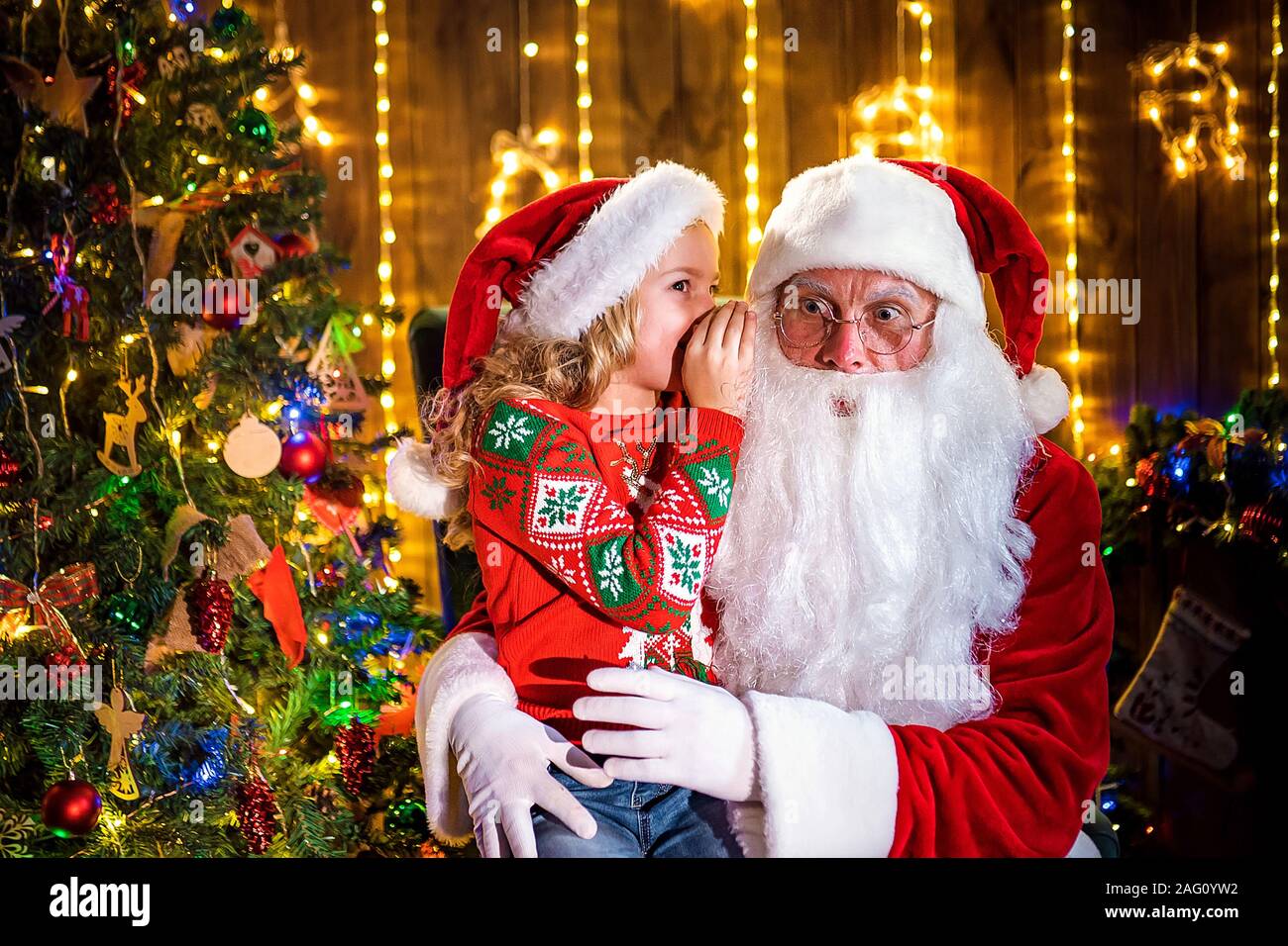 Little girl whispering in Santa's ear. Telling a secret. Revealing the ...